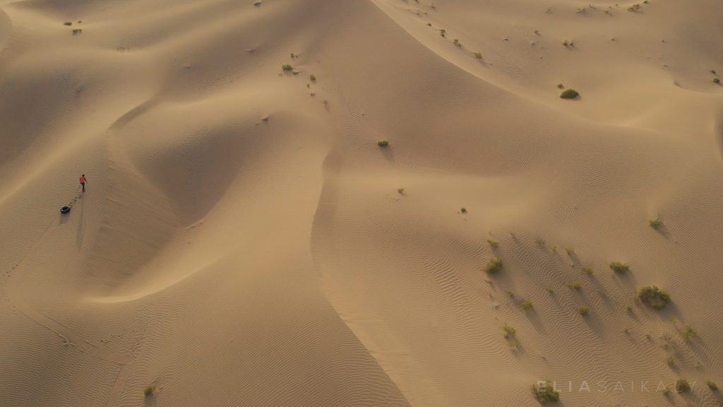 Climber pulling a tire in the desert overhead aerial - Elia Saikaly ...